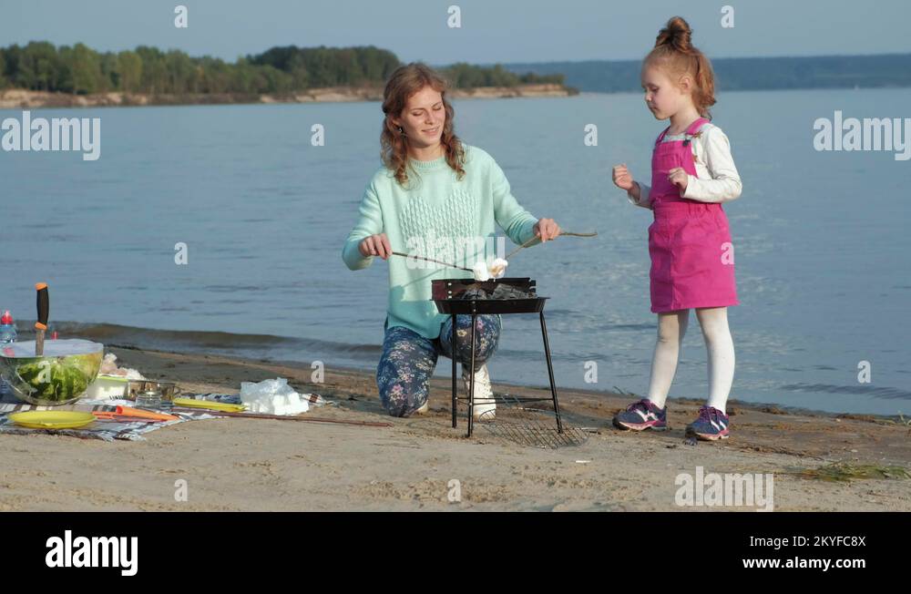 Mother and daughter fry marshmallows and vegetables on a barbecue on ...
