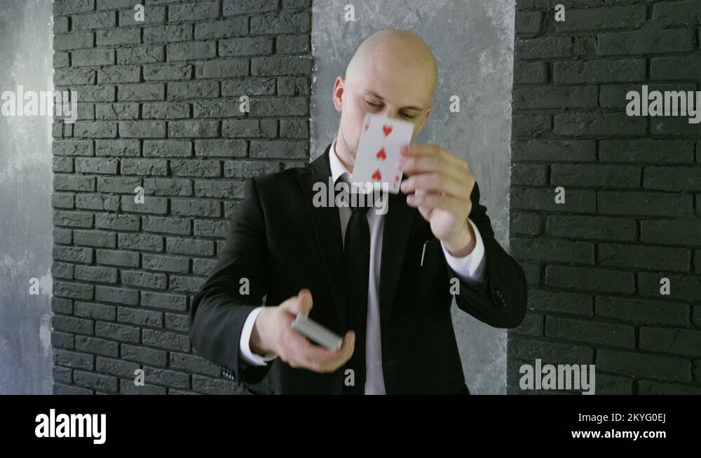 Magic. The man wearing in black suit showing trick with playing cards ...