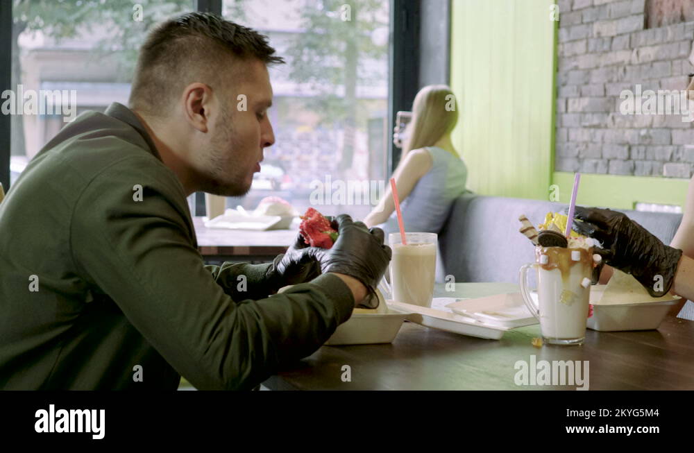Woman, man smiling, talking, eating burgers, drinking soft drinks in ...