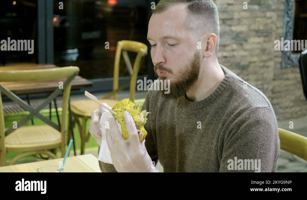 Burger. Handsome young man eating fast food, tasty hamburger in a ...