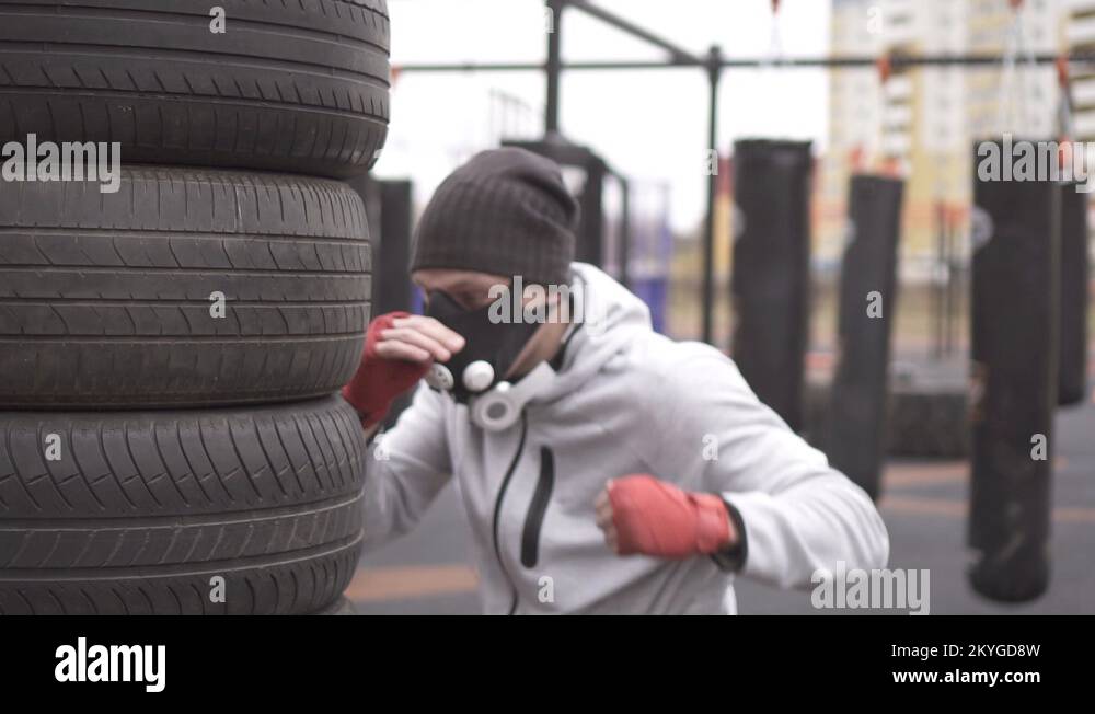 Man athlete in a training mask and boxing types boxing on the street ...