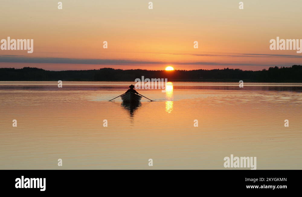 Amazing sun path reflection over the lake and silhouette of man rowing ...