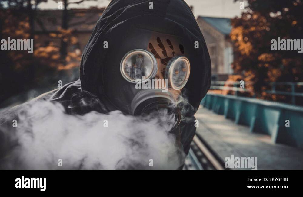 Man in hoody wears chemical warfare gas mask breathing smoke ...
