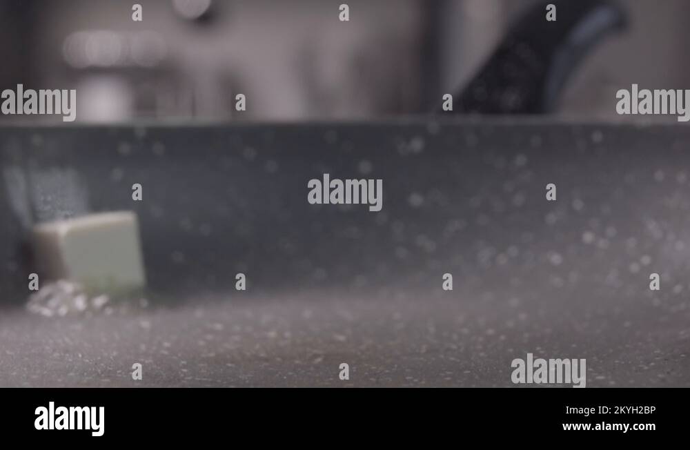 Sliding of the one piece of butter cube on frying pan and melting, slow ...