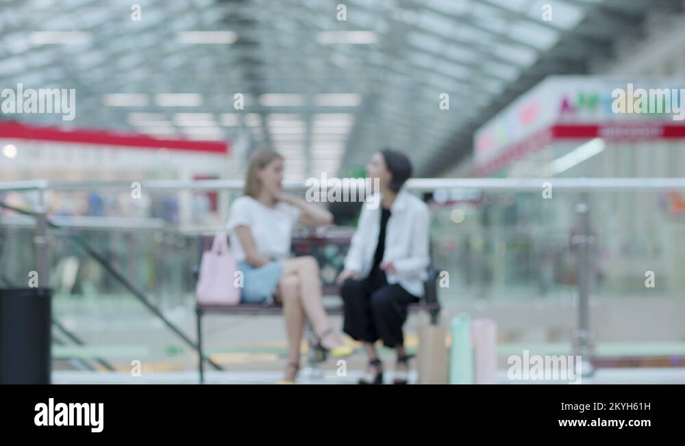 Two talkative young women sitting on bench in mall Stock Video Footage ...