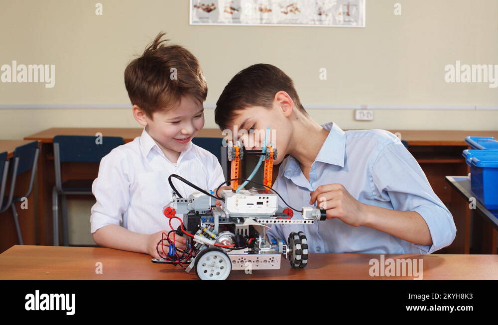 Two brothers kids playing with robot toy at school robotics class ...