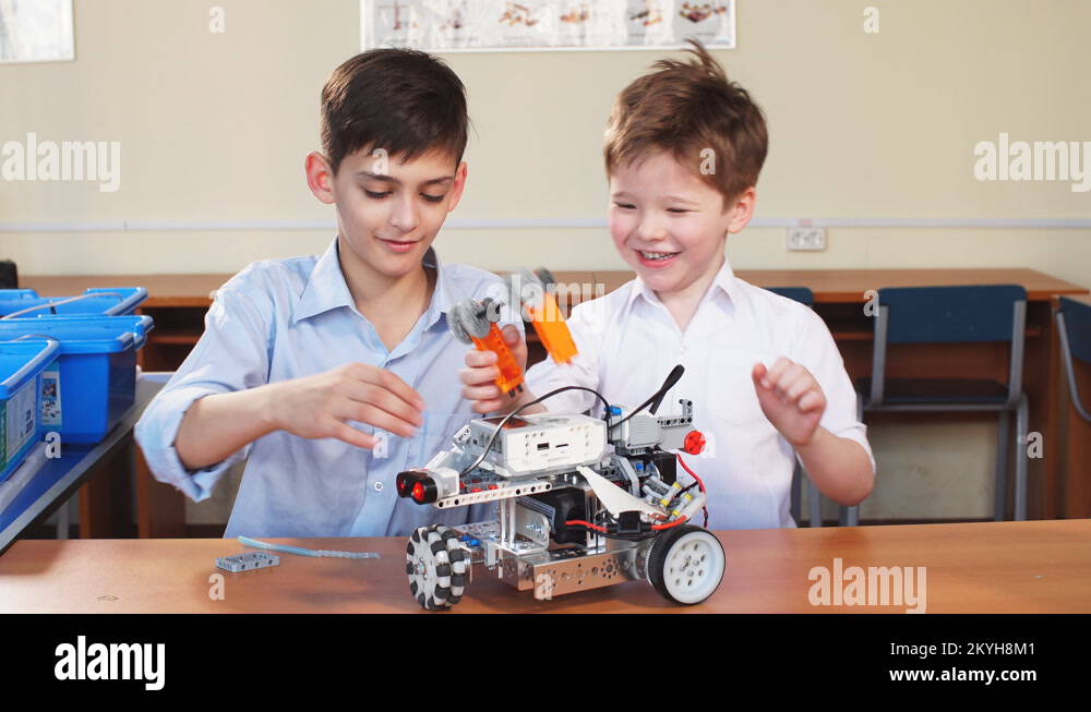 Two brothers kids playing with robot toy at school robotics class ...