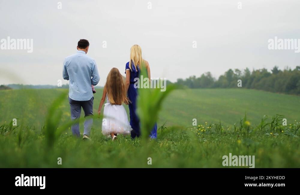 Portrait happy family goes on a green field with two children look ...