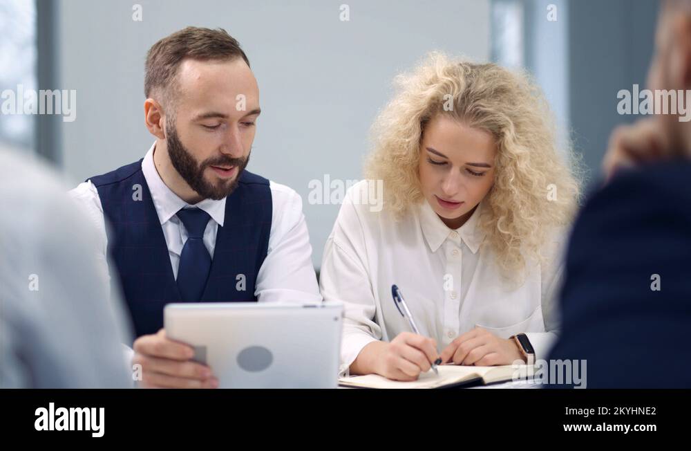 Smiling busy female writing text in notepad using pen from dictating of ...