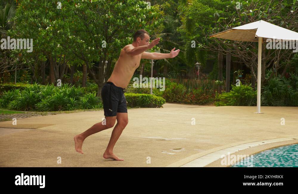 joyful young handsome man jumping into the pool, on vacation at the ...