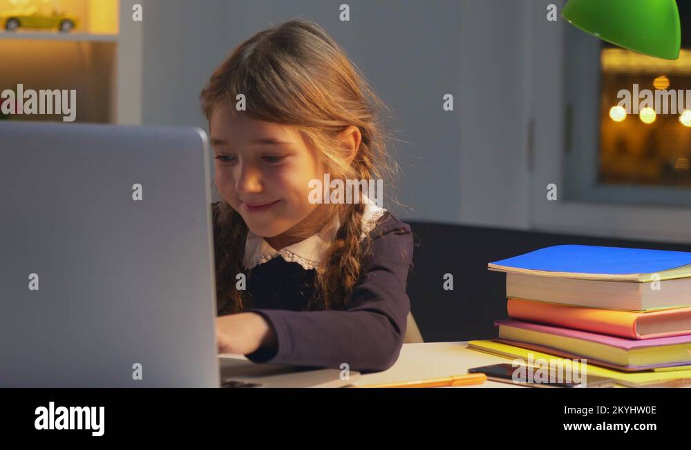 Little girl sitting at the desk in the child room and typing on a ...