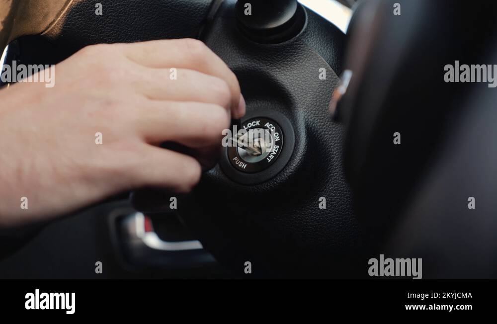 The man inside the car hand holds the key in the ignition, start the ...