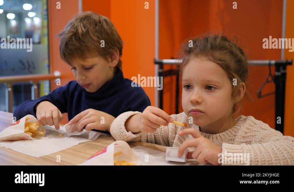 7 Children in fast food restaurant boy and girl together eating french ...