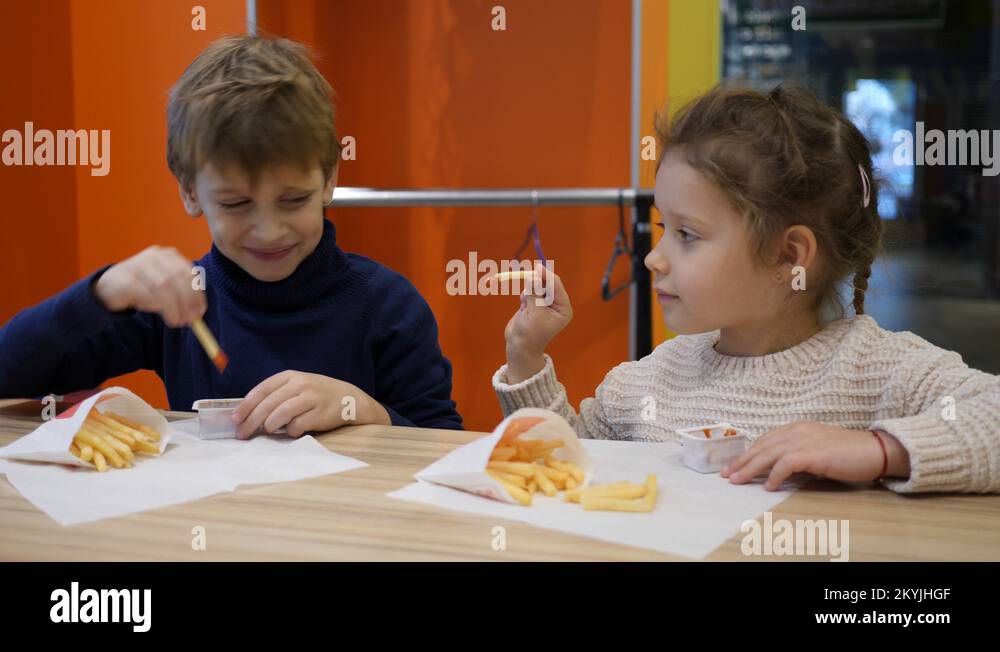 3 Fast food restaurant children boy and girl funny eat feed each other ...
