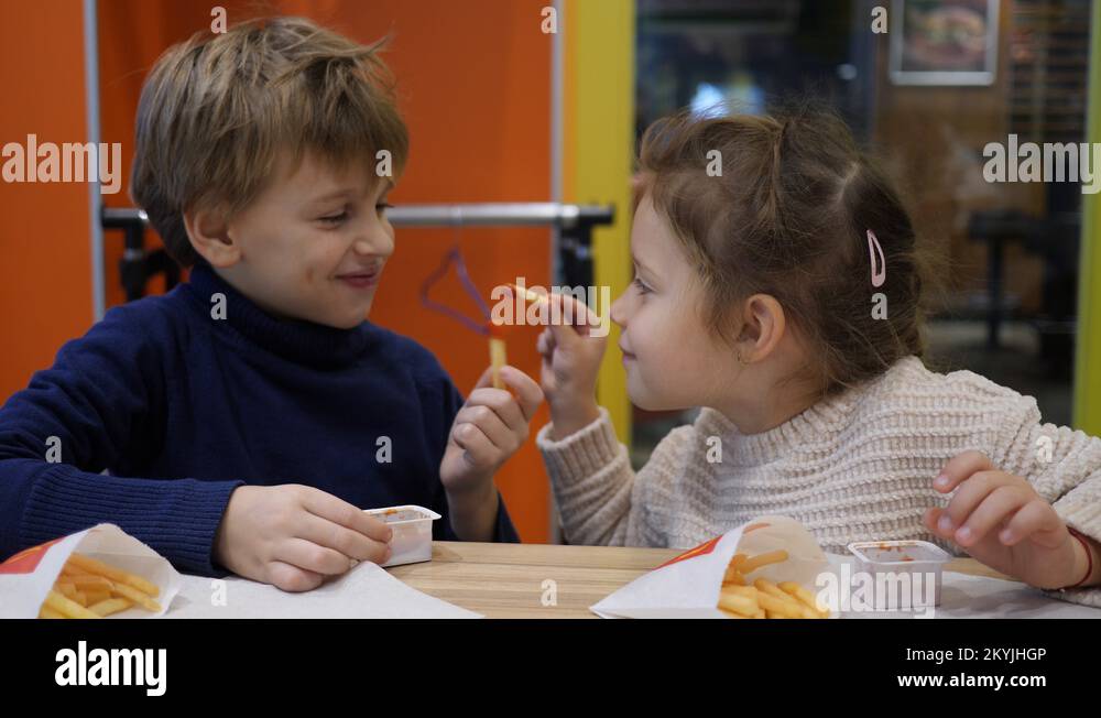 8 Fast food restaurant children boy and girl funny eat feed each other ...