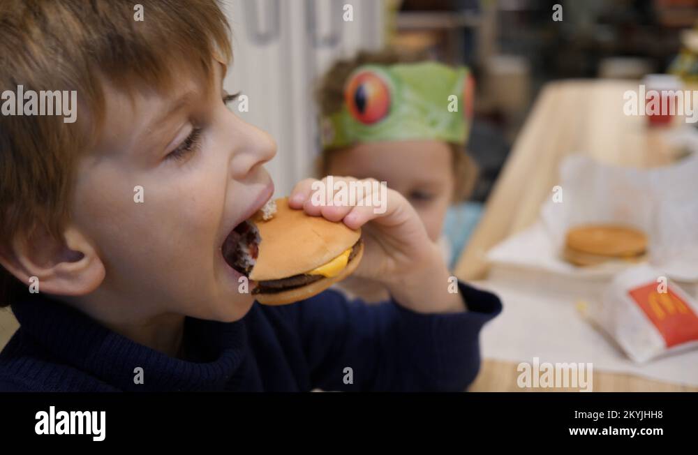 3 Children in fast food restaurant boy and girl together eating burgers ...