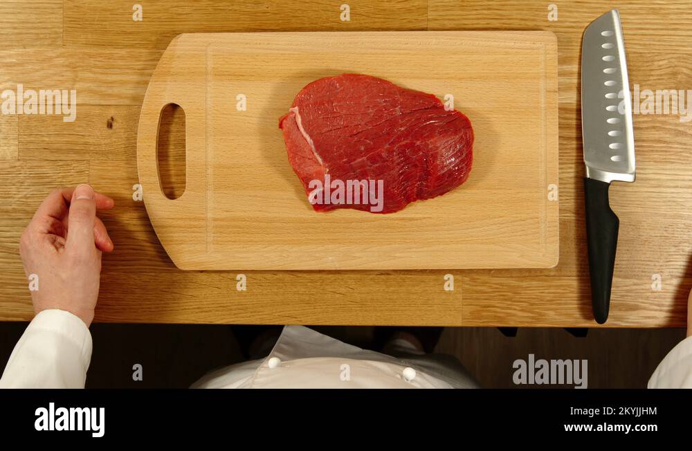 TOP VIEW: Cook takes knife and cuts beef into slices and then into ...