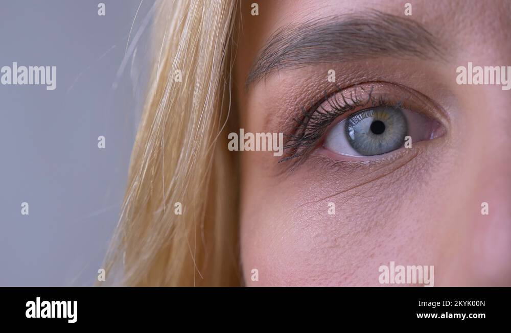 Close-up half portrait of womans right blue eye watching directly into ...