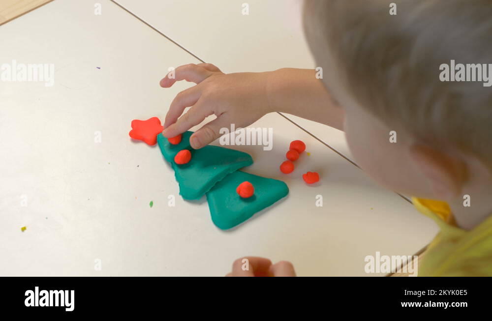 A 2-year-old preschool kid making christmas tree from modeling clay ...