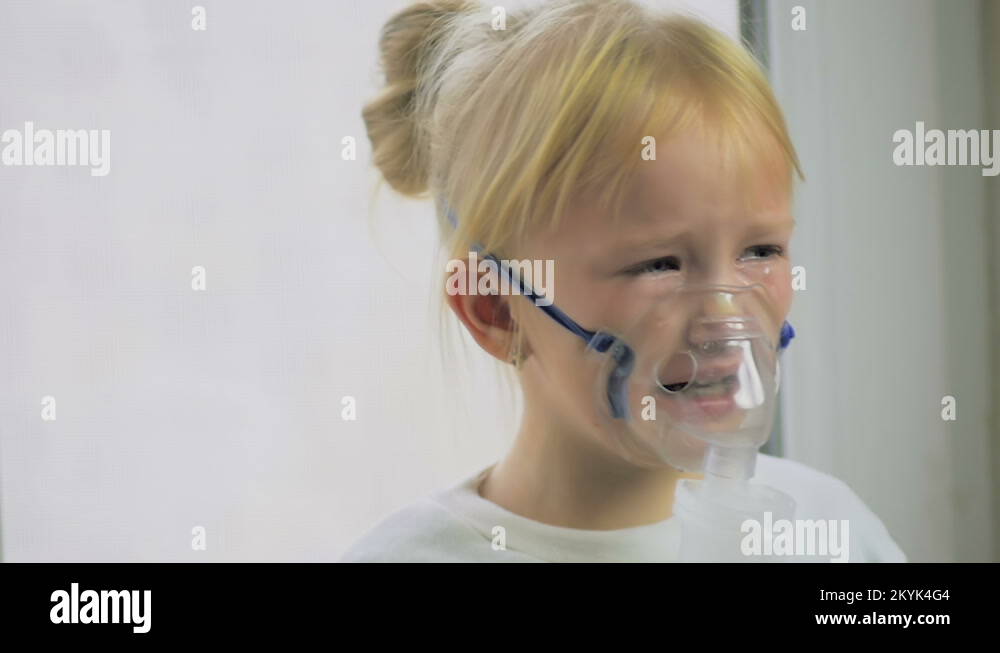 Four-year-old girl in a mask breathing gas through an inhaler in the ...