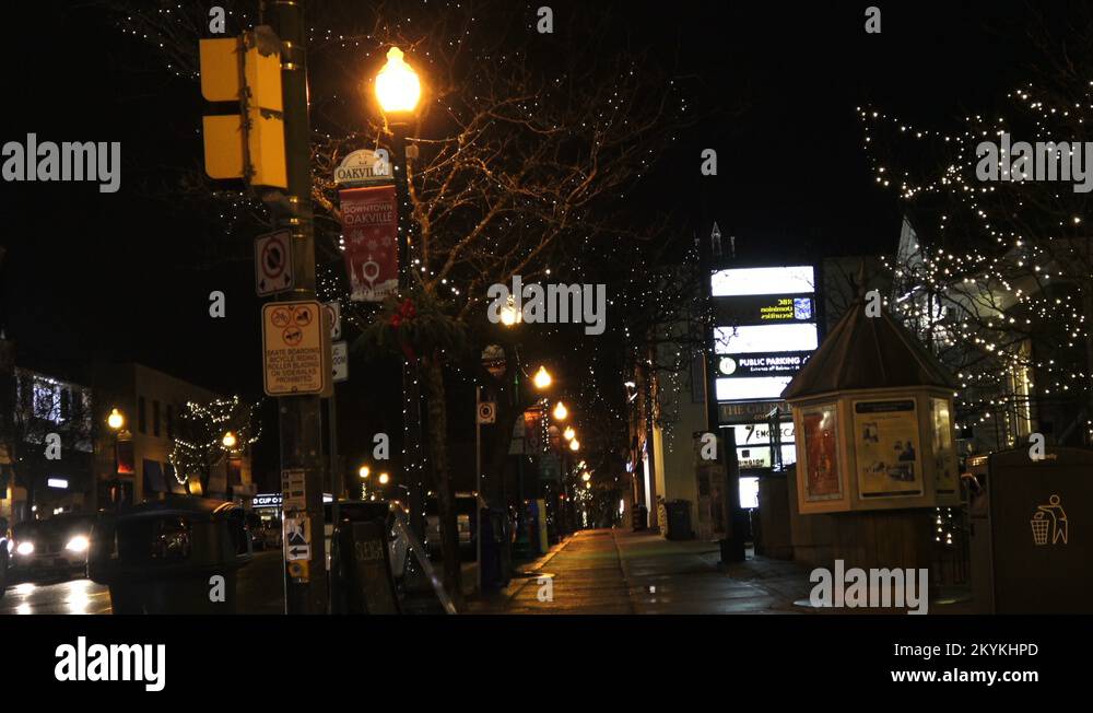 Well-lit sidewalk in the city at night with lights on trees for the ...