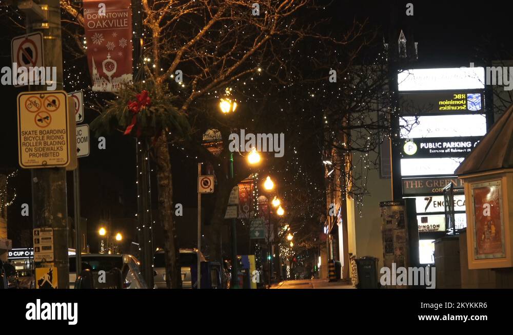 Well-lit sidewalk in the city at night with lights on trees for the ...