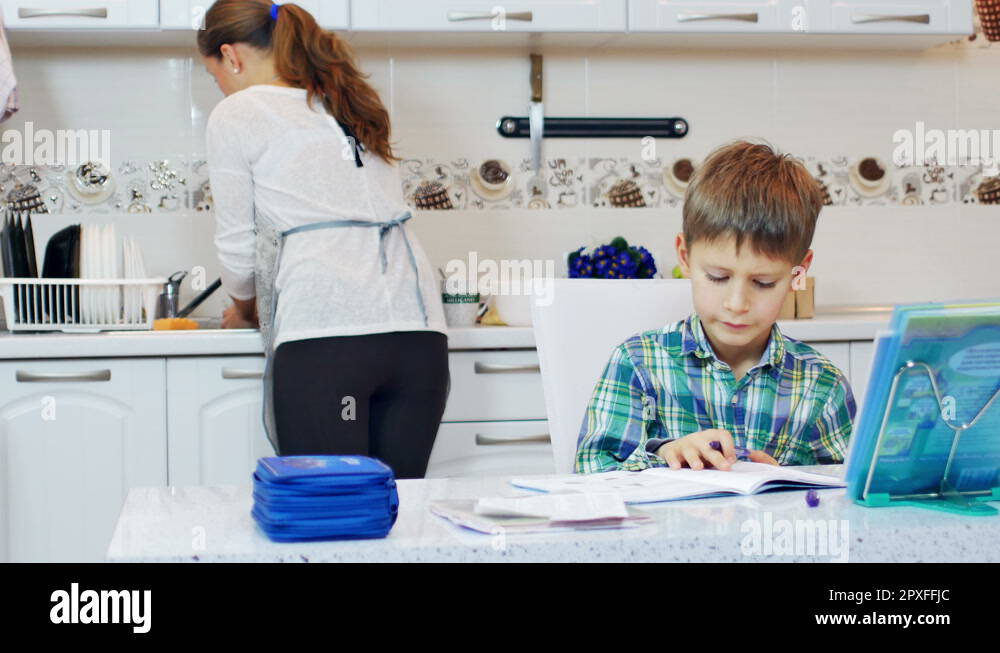 Little boy doing homework in the kitchen with his mother Stock Video ...