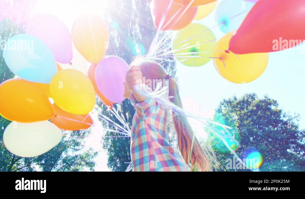 Closeup portrait with Lens flare. Girl spinning with balloons. Sunlight ...