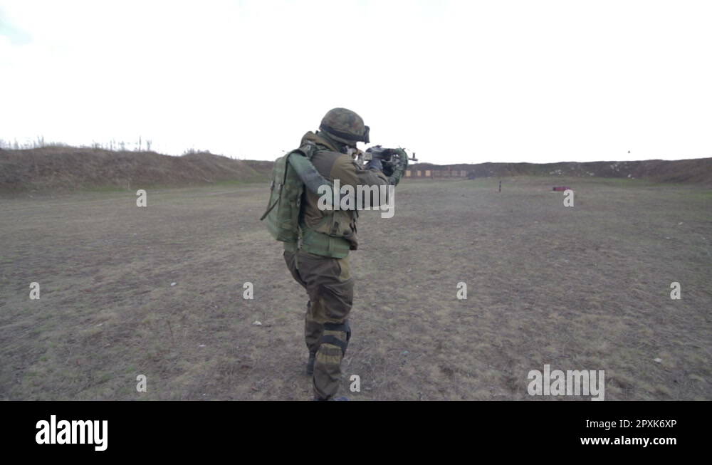 A soldier with a machine gun on a military firing range shooting at a ...