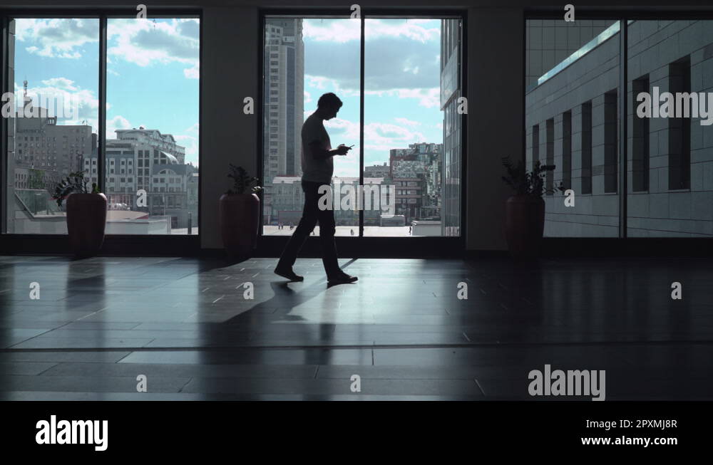 The young man goes down a long corridor room with high windows in which ...