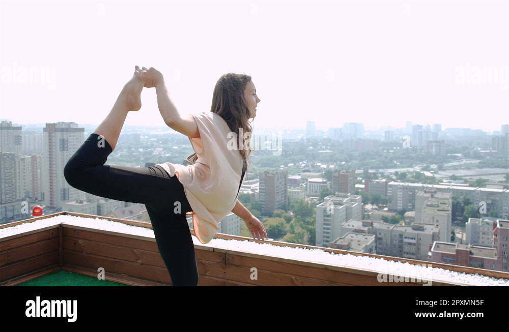 Beautiful woman doing a yoga exercise on he rooftop of a skyscraper ...