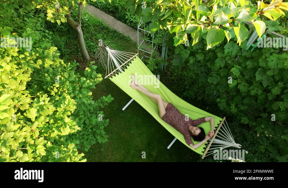 Garden. A young dark-haired woman resting in a hammock. Top view. 4K ...