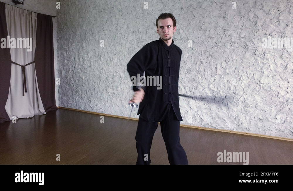 Man practicing elements of tai chi. A man rotating steel swords around ...