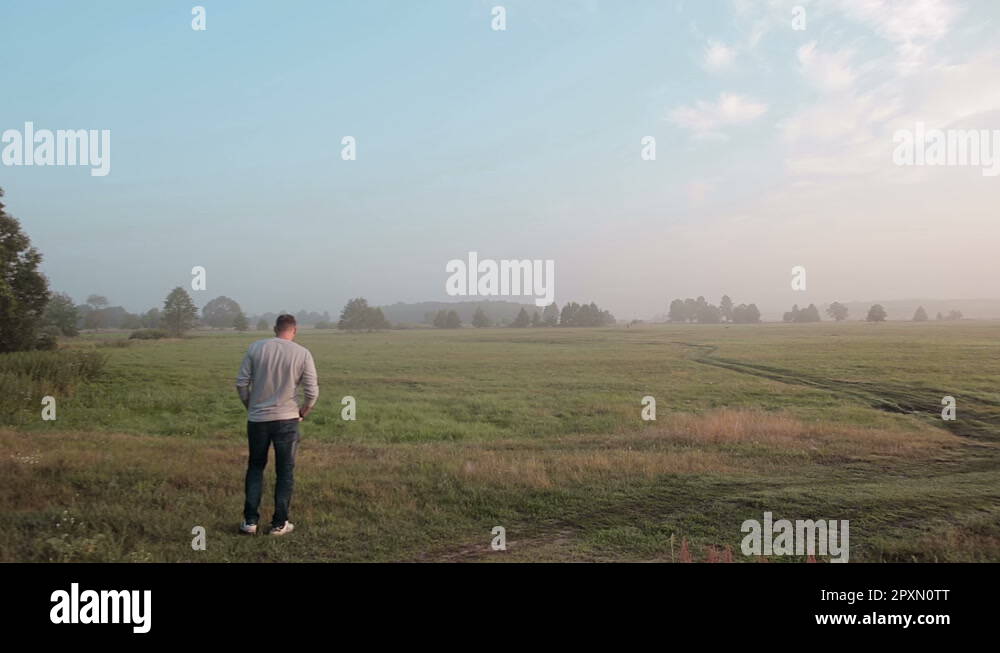 A back view of a tall man enjoying quiet time in the nature. He is ...