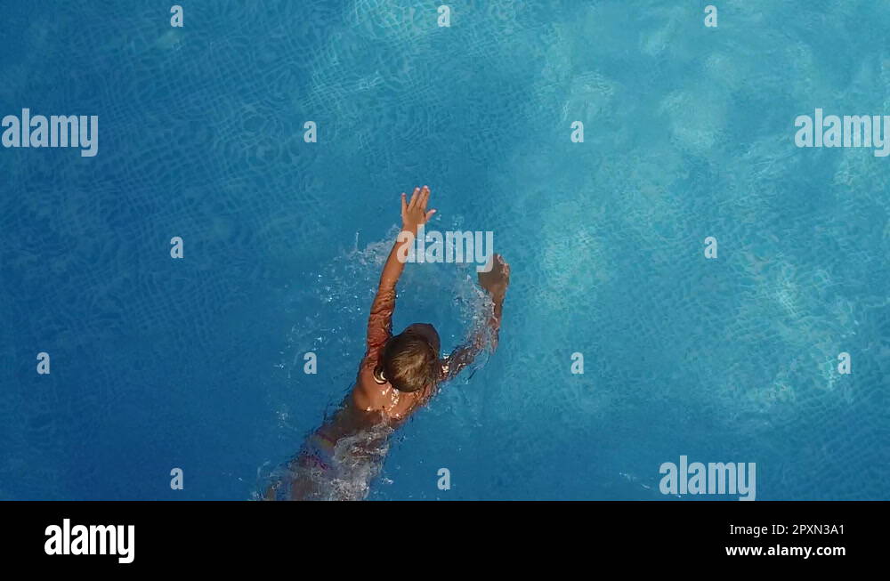Swimming pool. Little girl is swimming in the pool. Slow motion. Top ...