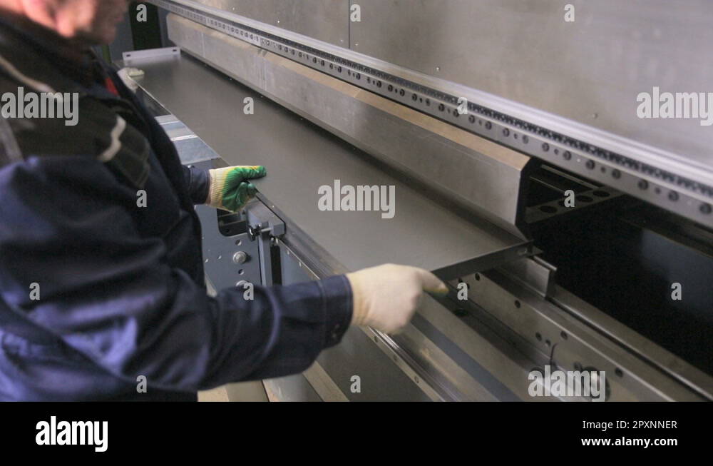 Worker hands bend metal sheet on a modern bending industrial machine at ...