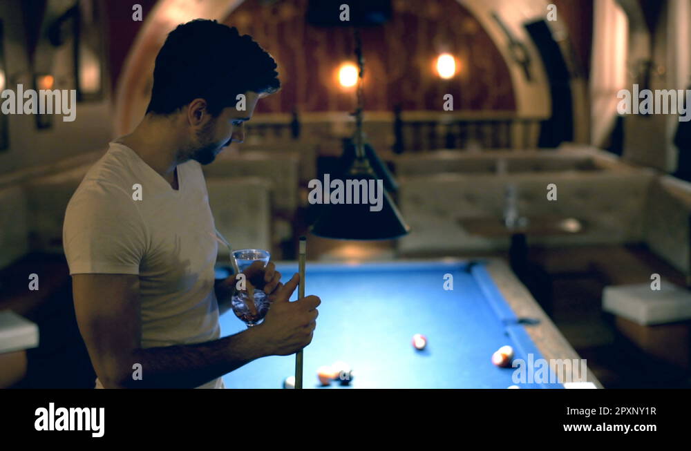 Man standing next to the billiard's table and drinking alcoholic ...