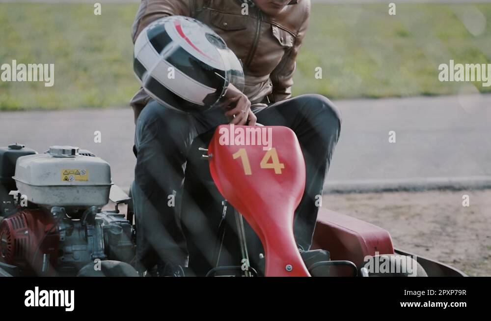 Go-kart track. Man is getting in a kart, shows a thumb up, prepares to ...