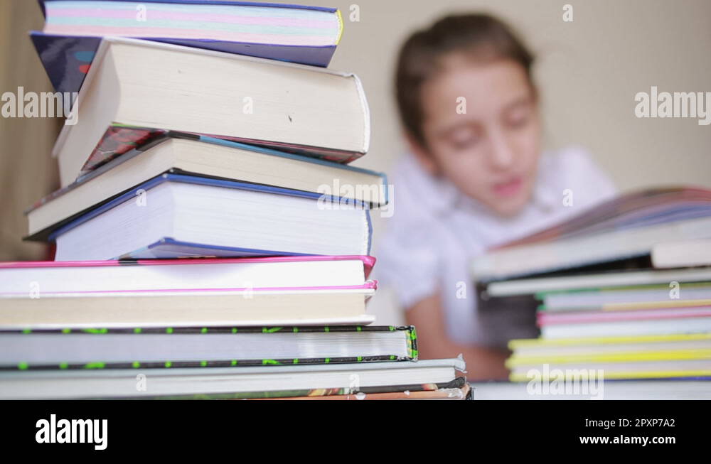 little girl in school uniform is reading a book, sitting between piles ...