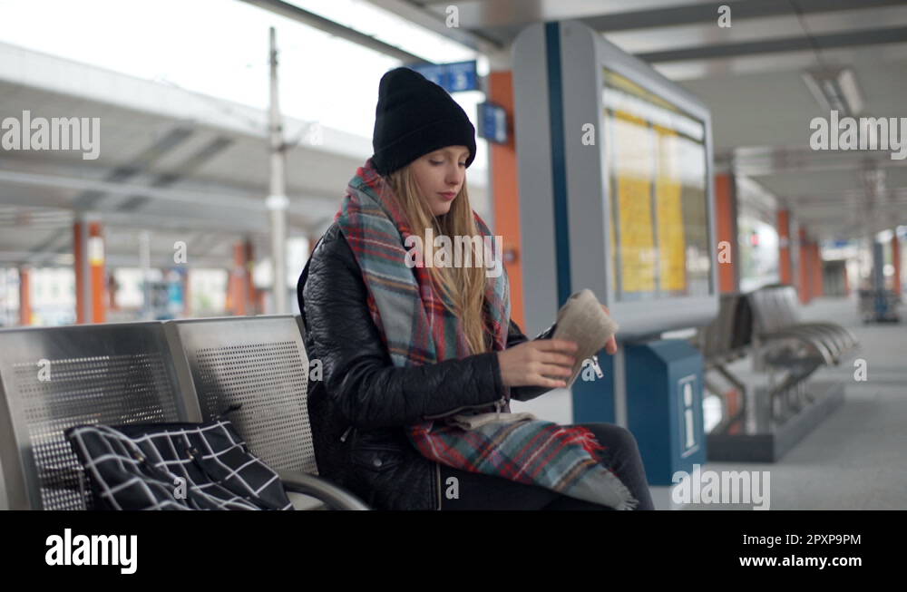 Girl looking very cold while sitting on a platform and putting gloves ...