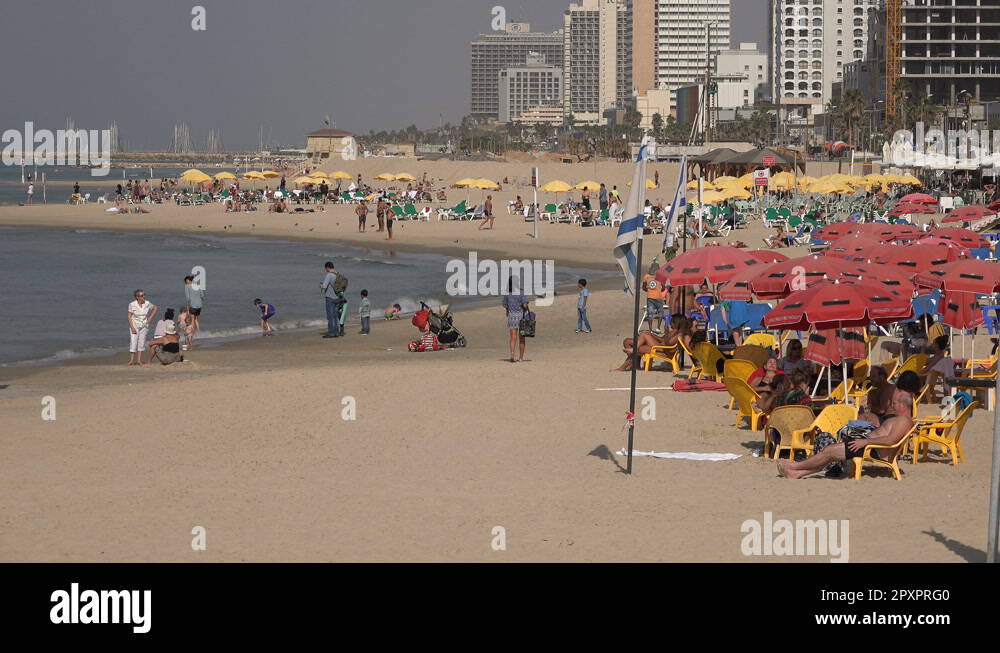 People sunbathing on busy beach of Tel Aviv, national flags Israel ...