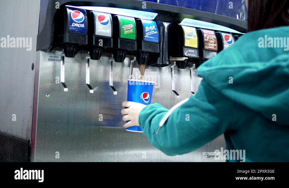 Young woman selecting cool fountain drink from self service soda ...