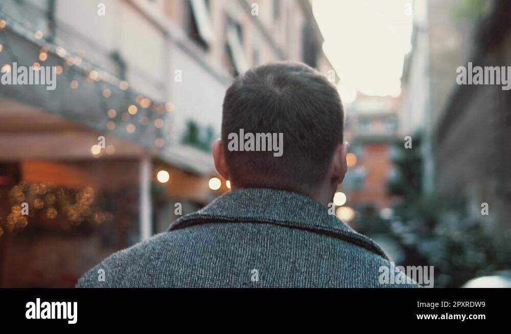 Back view of young man walking at city street in Europe. Stylish guy ...
