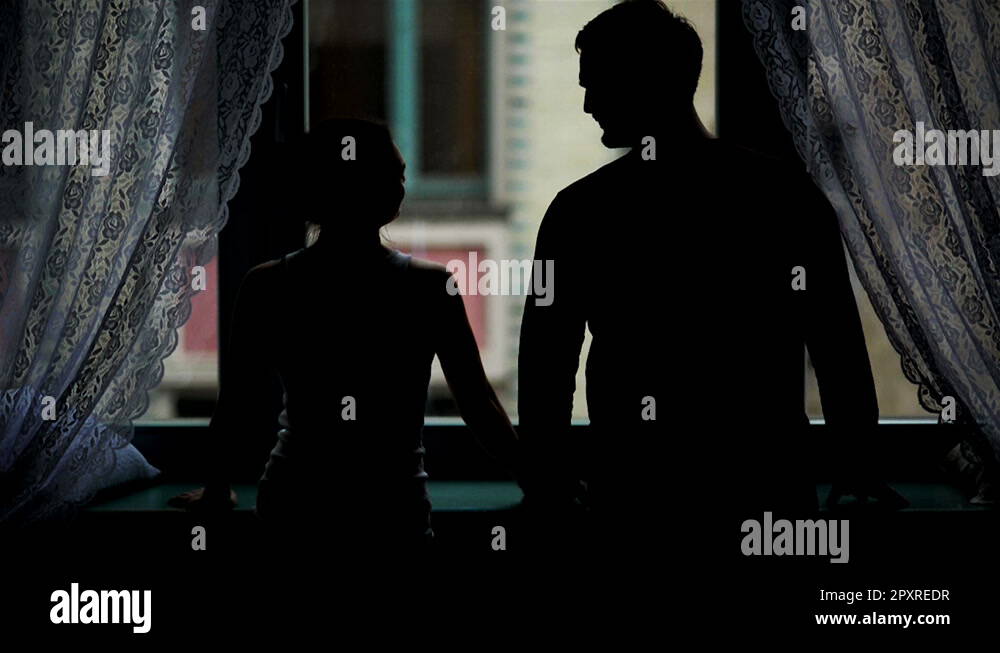 Back View of Romantic Couple Standing near the Window in the Darkness ...