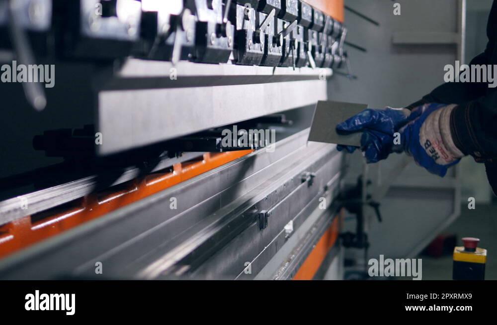 Worker bend metal sheet on a modern bending industrial machine at a ...