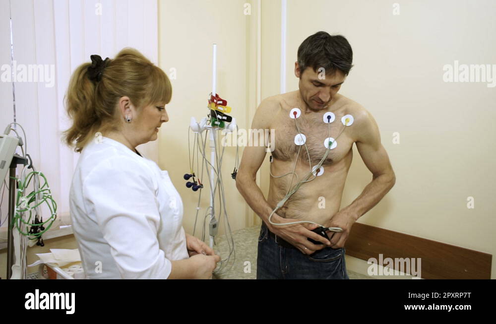 Doctor attaching electrodes on patient's chest to monitor an ...