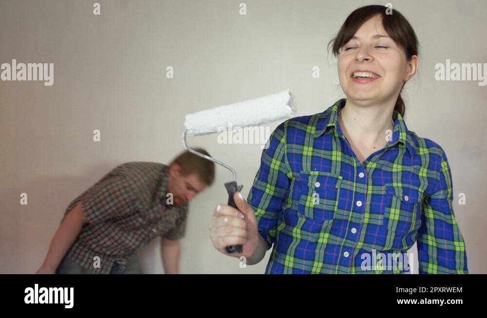 The family of mom, dad, daughter paint wall using paintbrush and roller ...