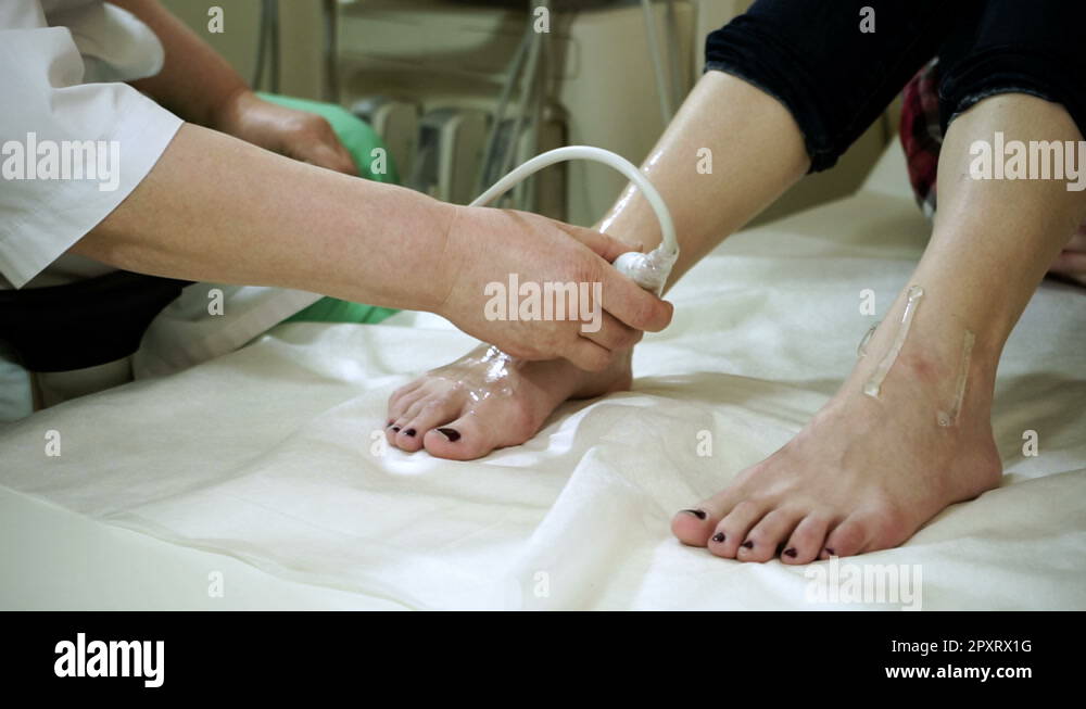 Female doctor examining the woman's right foot using an ultrasound ...