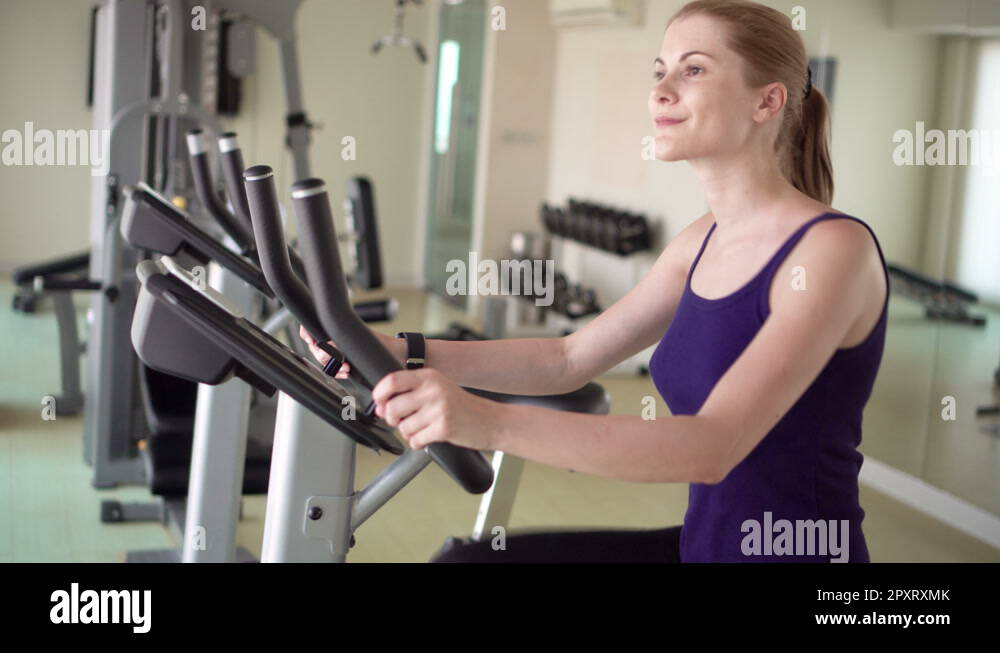 Beautiful fit young woman in a gym doing exercises on a velosimulator ...