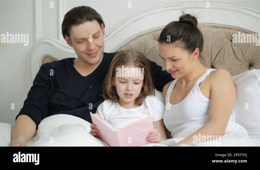 Beautiful Little Girl is Reading Aloud the Book Lying on the Bed with ...